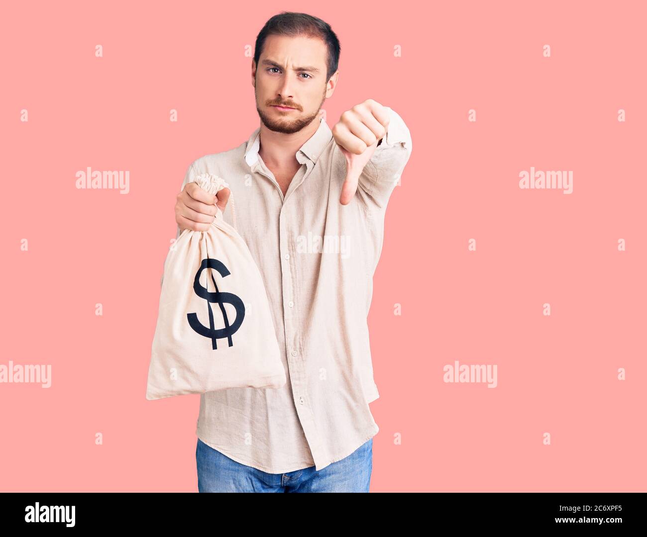 Young handsome caucasian man holding money bag with dollar symbol with ...