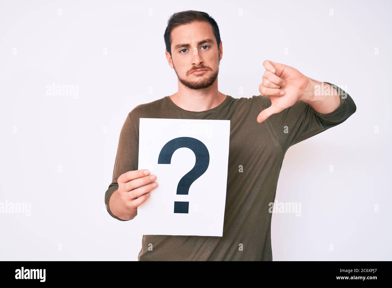 Young handsome man holding question mark with angry face, negative sign ...