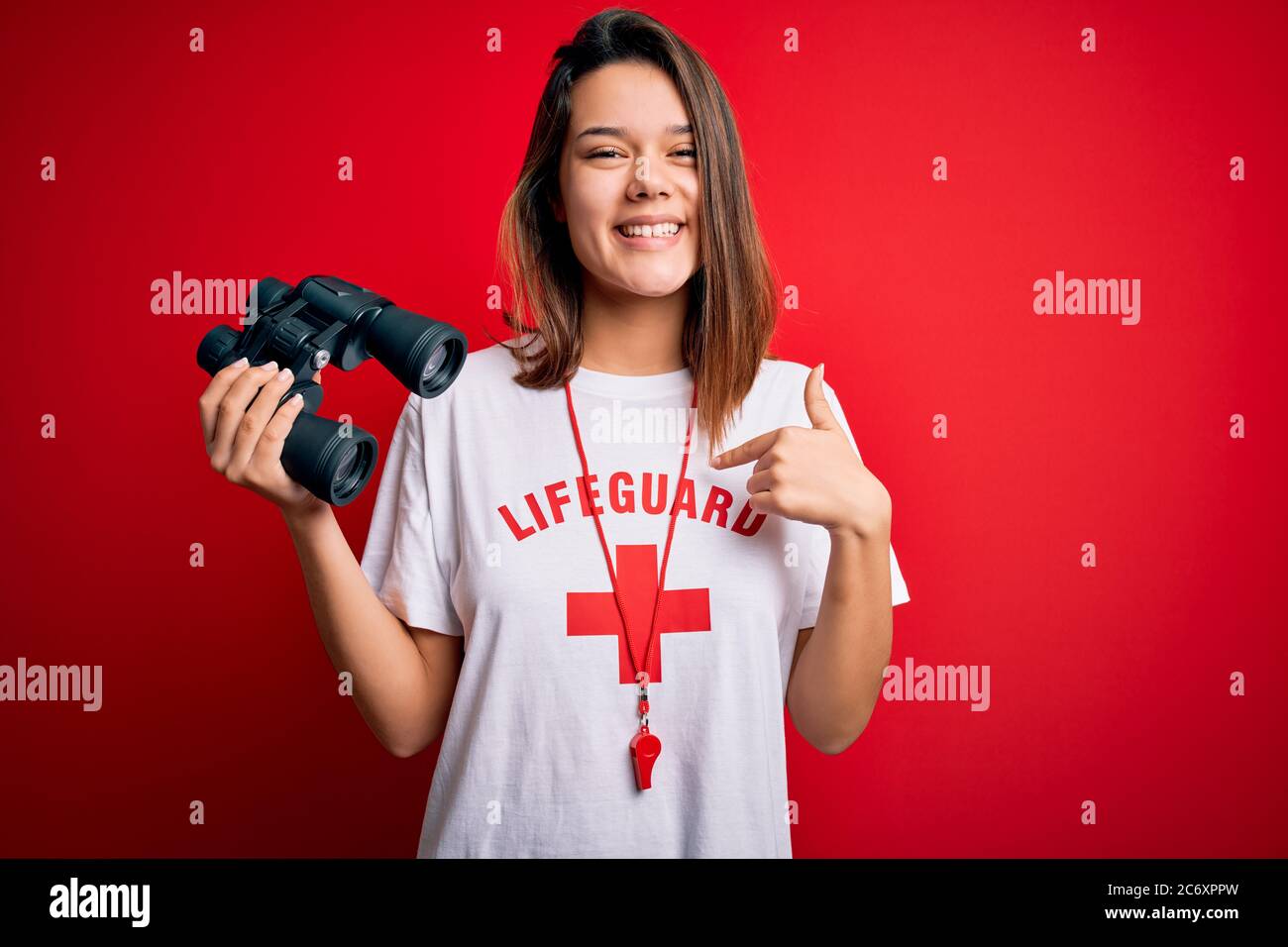 Young beautiful lifeguard girl wearing whistle using binoculars over ...