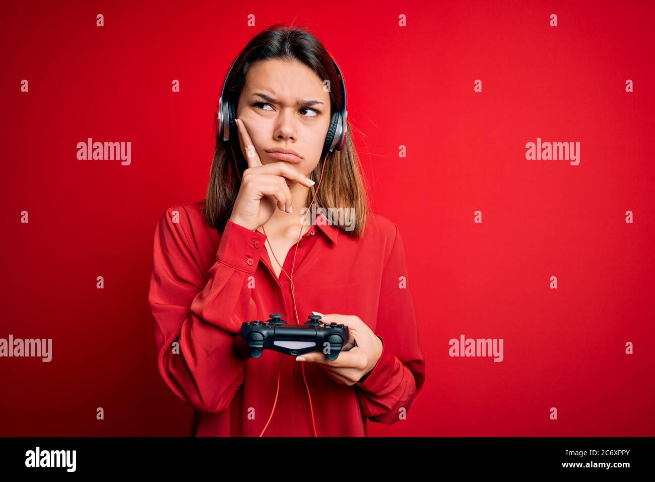 Young beautiful brunette gamer girl playing video game using joystick ...