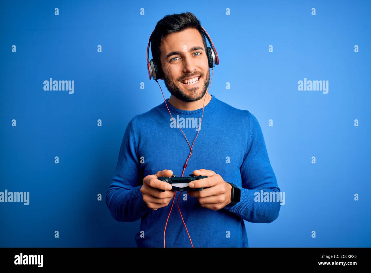Young handsome gamer man with beard playing video game using joystick ...