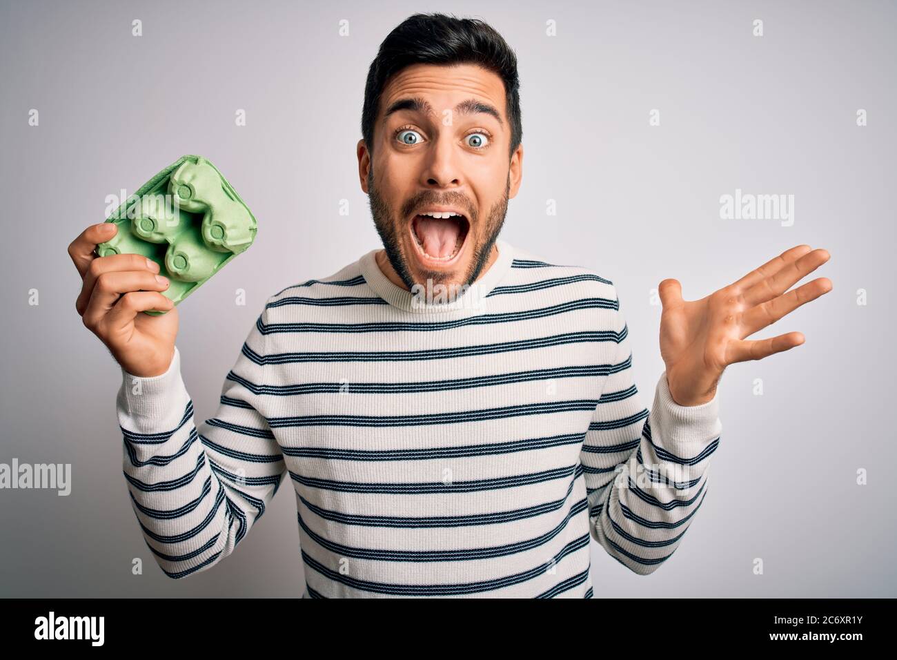 Young handsome man with beard holding carton box of fresh eggs over ...