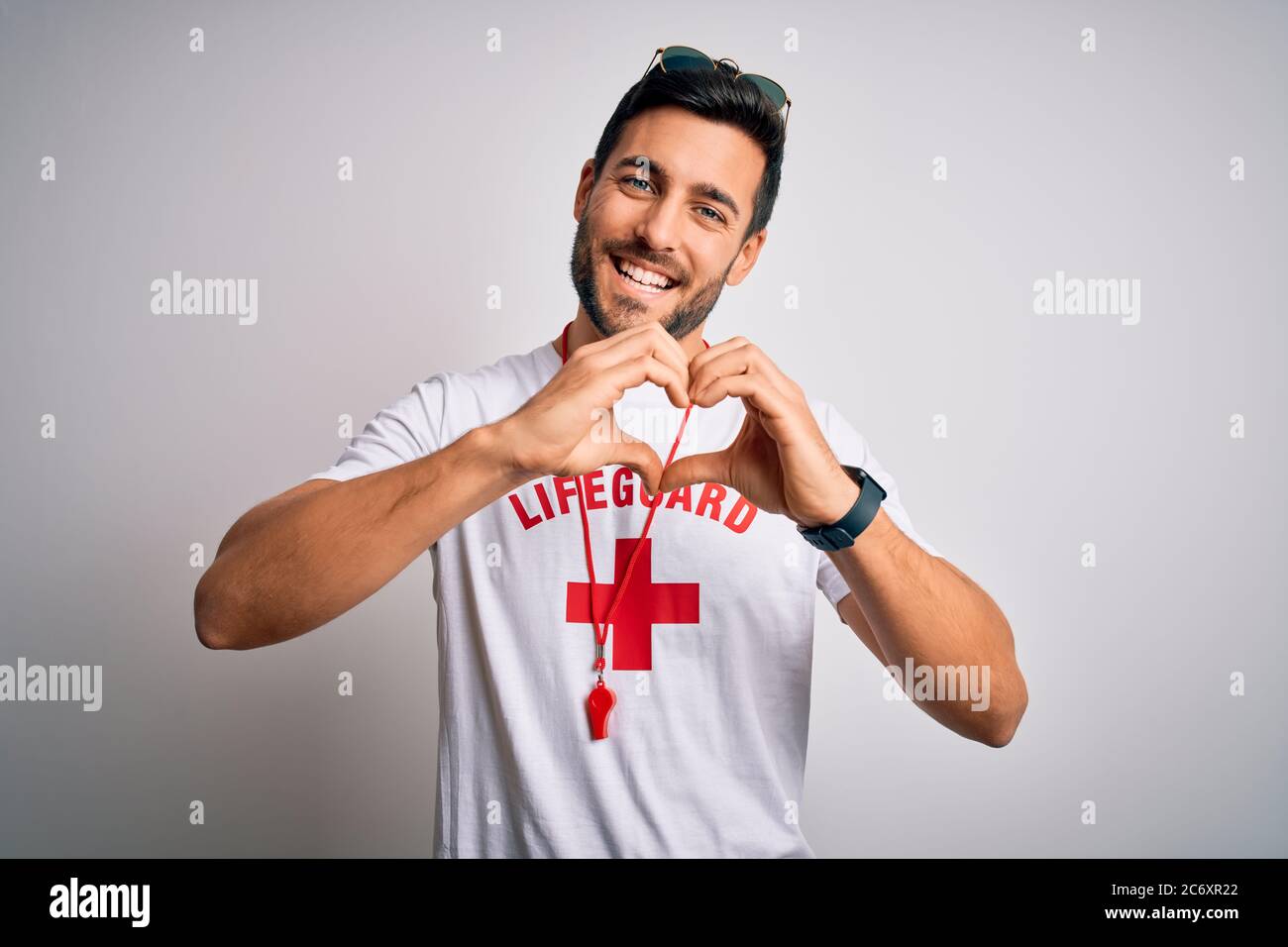 Young handsome lifeguard man with beard wearing t-shirt with red cross ...