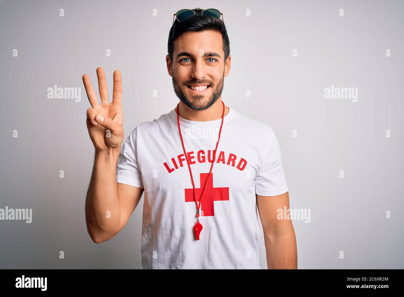 Young handsome lifeguard man with beard wearing t-shirt with red cross ...