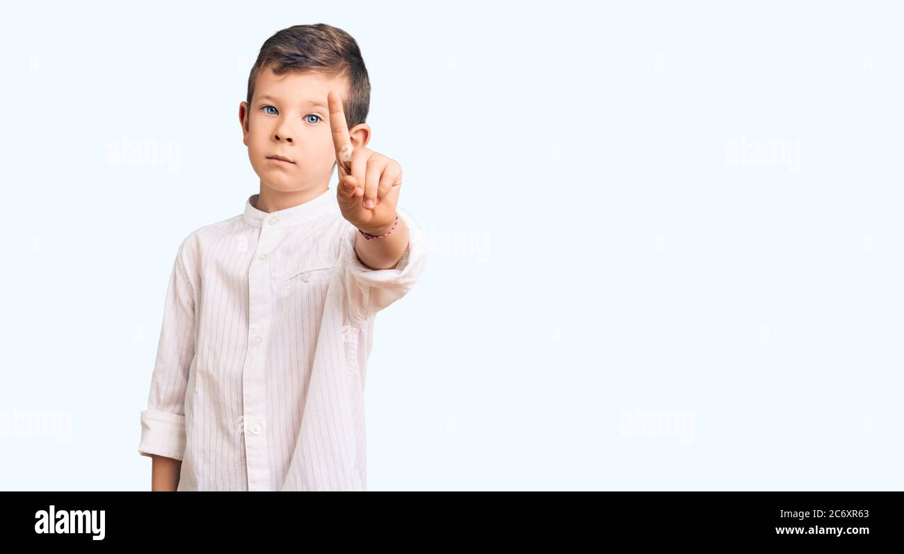 Cute blond kid wearing elegant shirt pointing with finger up and angry ...