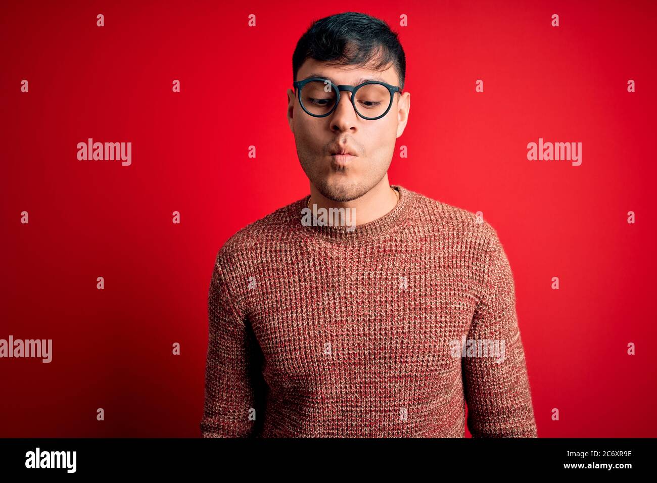 Young handsome hispanic man wearing nerd glasses over red background ...