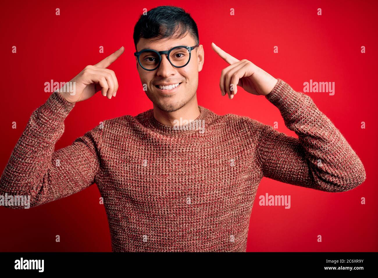 Young handsome hispanic man wearing nerd glasses over red background ...