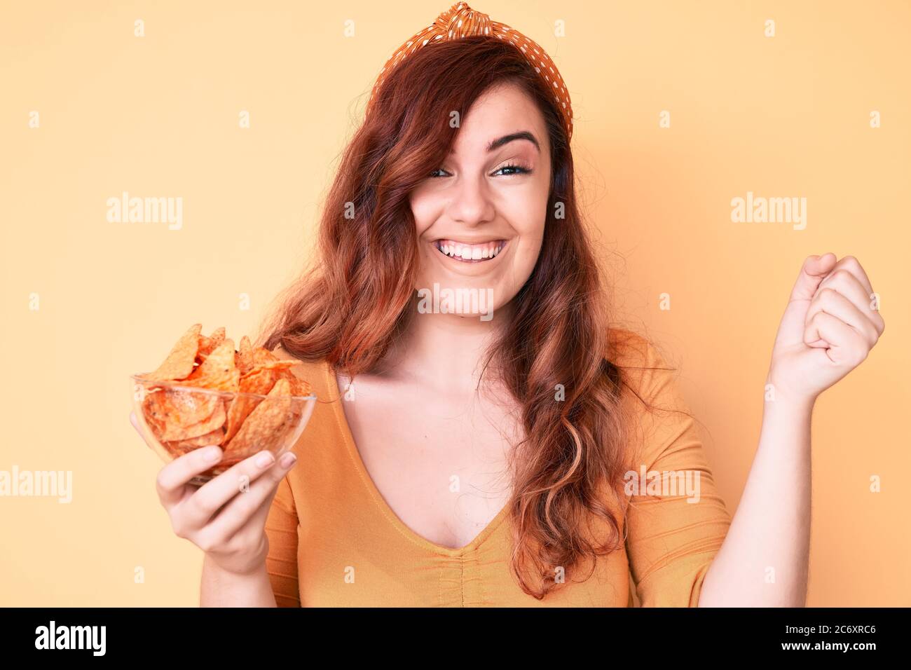 Young beautiful woman holding nachos potato chips screaming proud ...