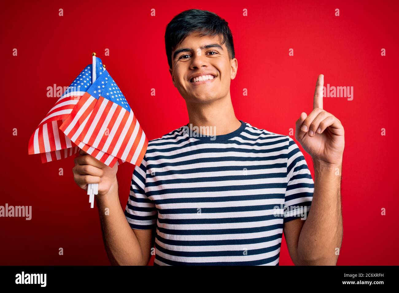 Young handsome patriotic man holding united states flags celebrating ...