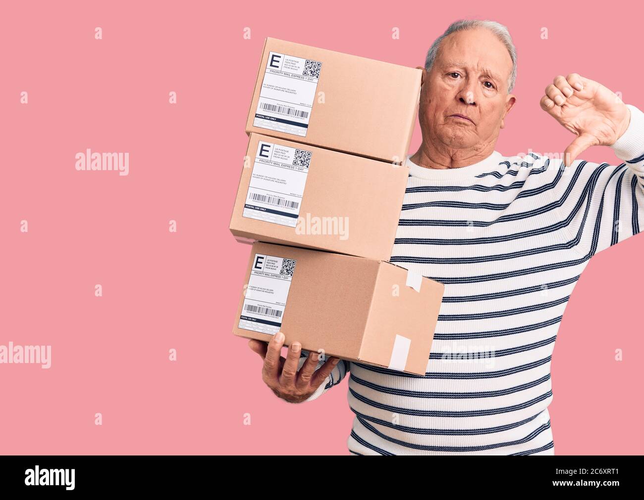 Senior handsome grey-haired man holding delivery boxes with angry face ...