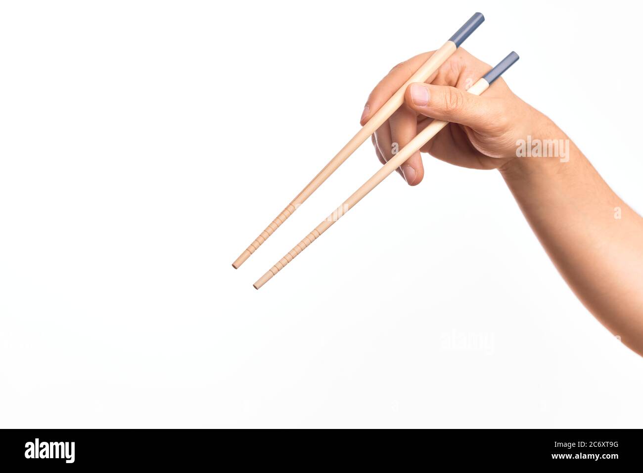 Hand of caucasian young man holding chopsticks over isolated white ...