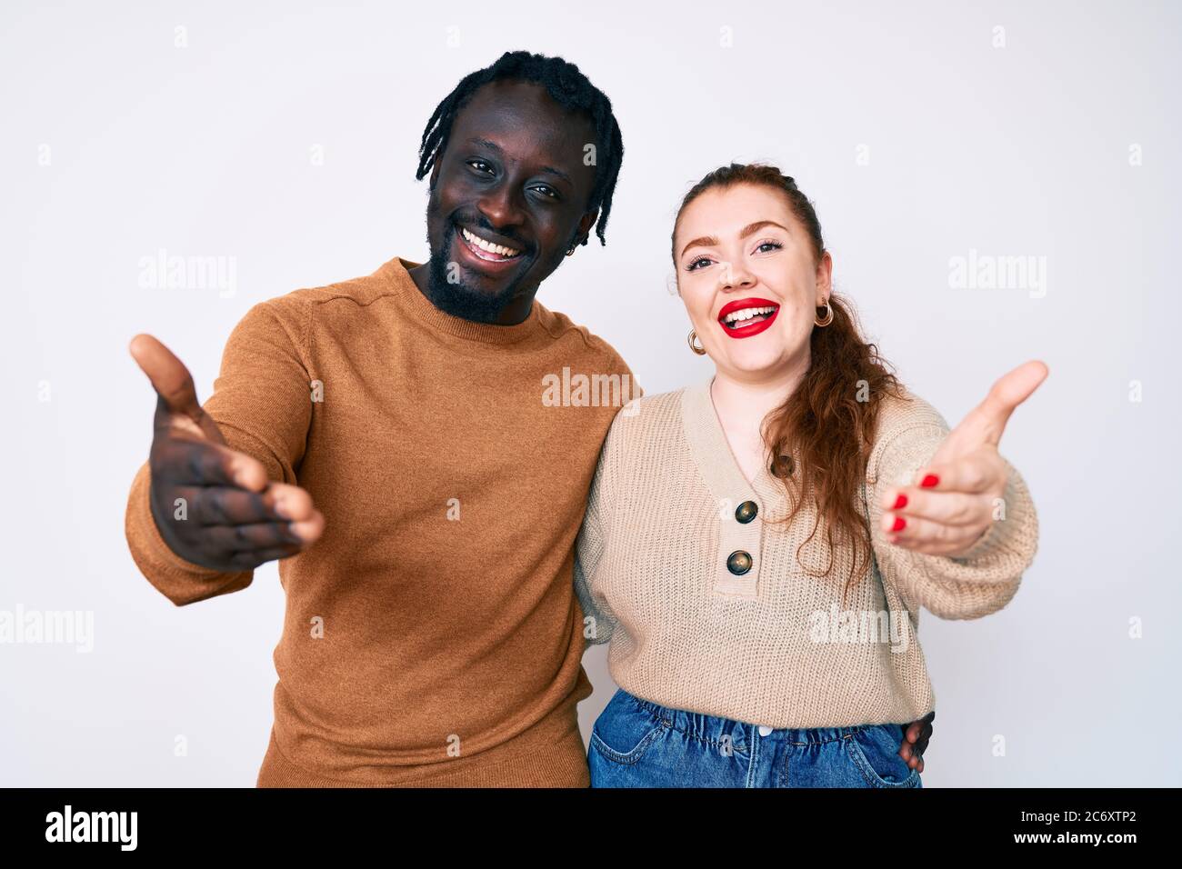Interracial couple wearing casual clothes smiling friendly offering ...