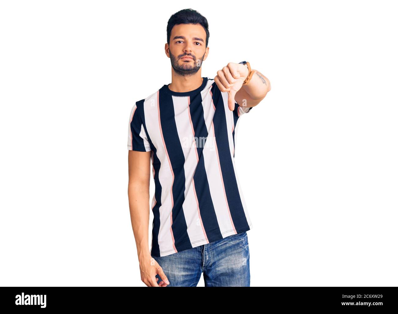 Young handsome hispanic man wearing striped tshirt looking unhappy and ...