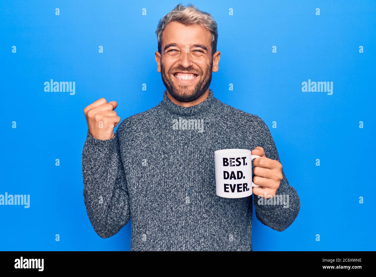 Handsome blond man drinking cup of coffee with best dad ever message ...