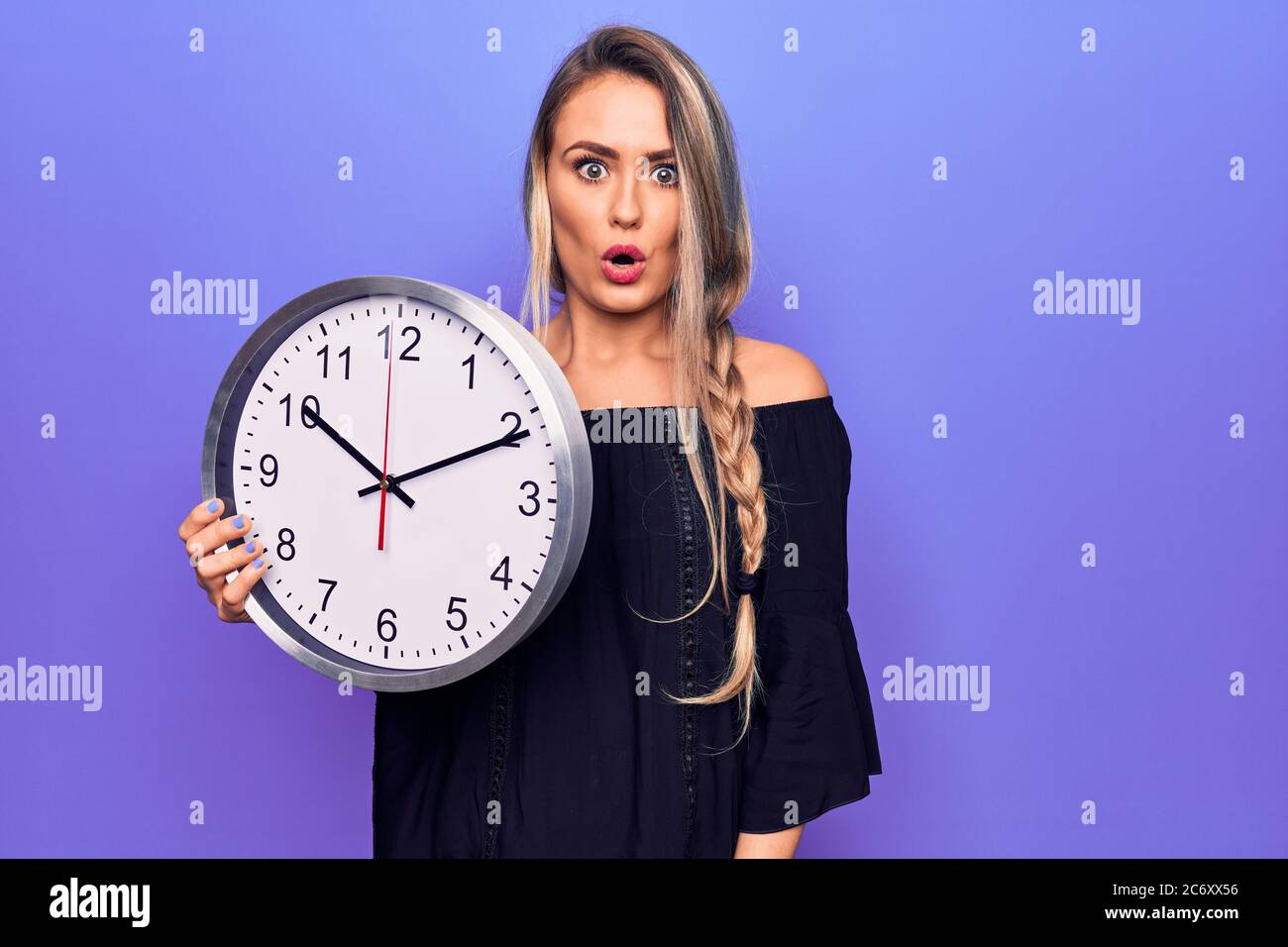 Young beautiful blonde woman doing countdown using big clock over ...