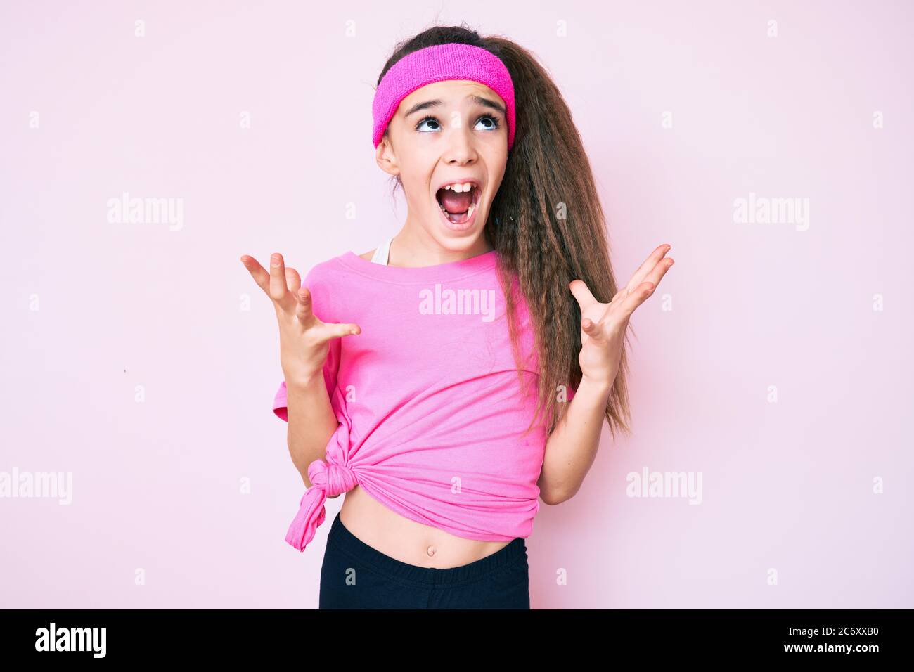 Cute hispanic child girl wearing sportswear crazy and mad shouting and ...
