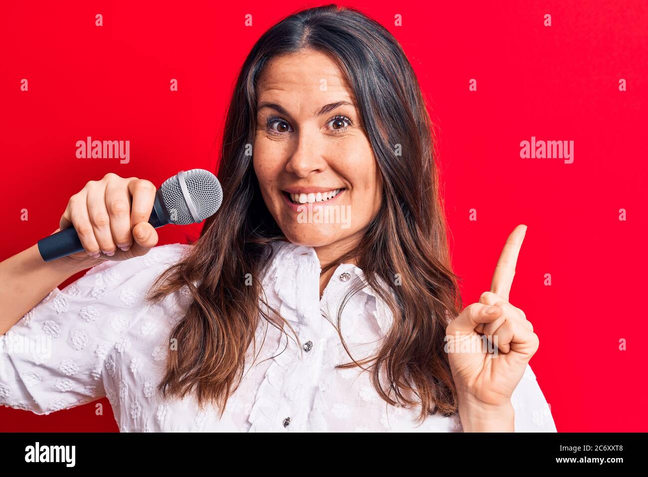 Young beautiful brunette singer woman singing song using microphone ...
