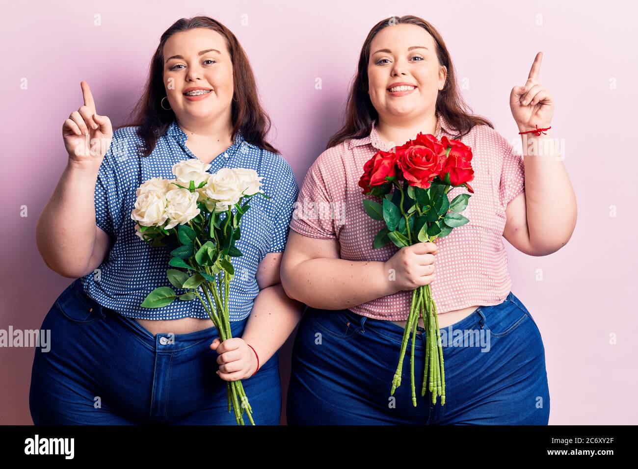 Young plus size twins holding flowers surprised with an idea or ...