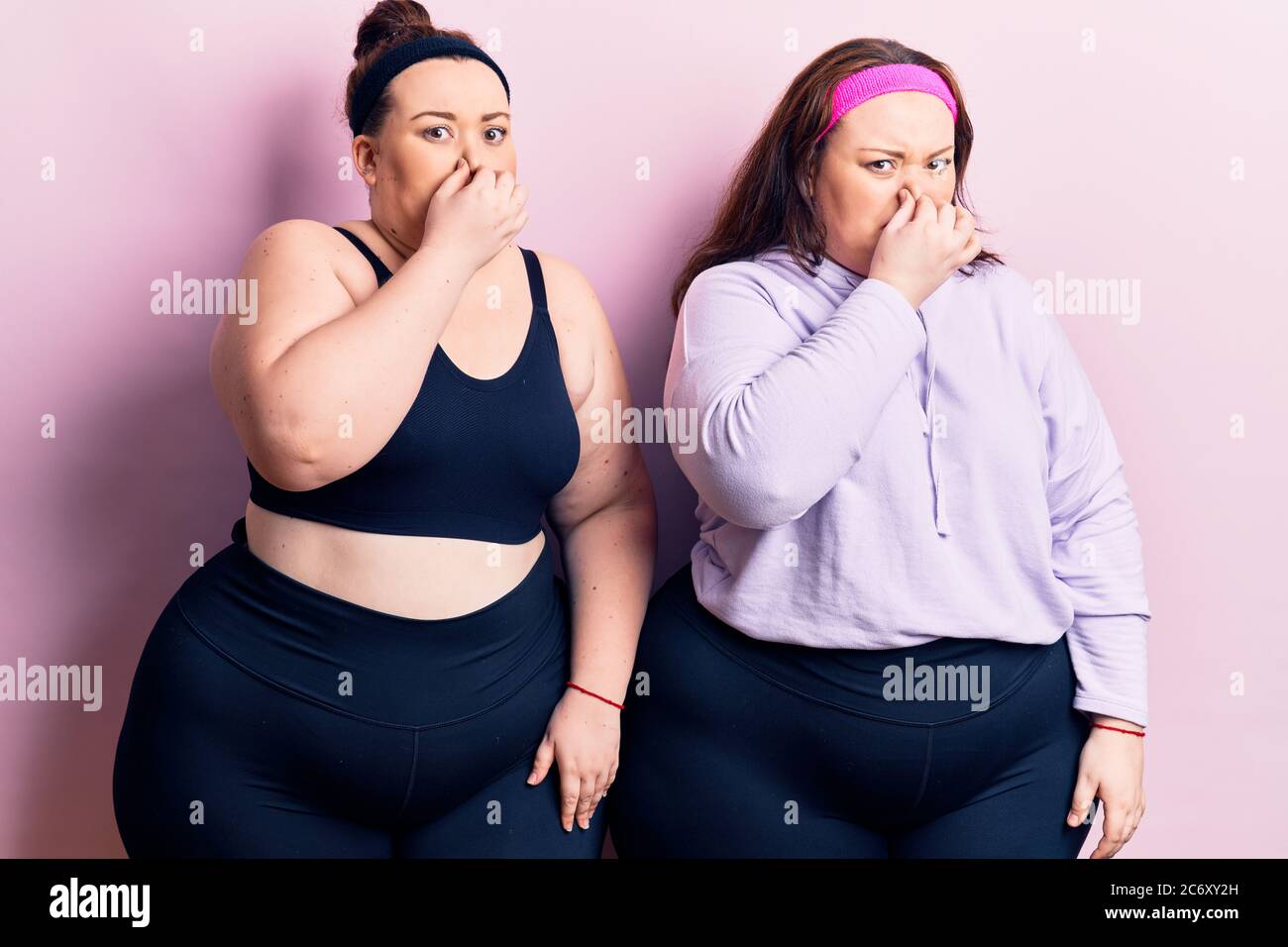 Young plus size twins wearing sportswear smelling something stinky and ...