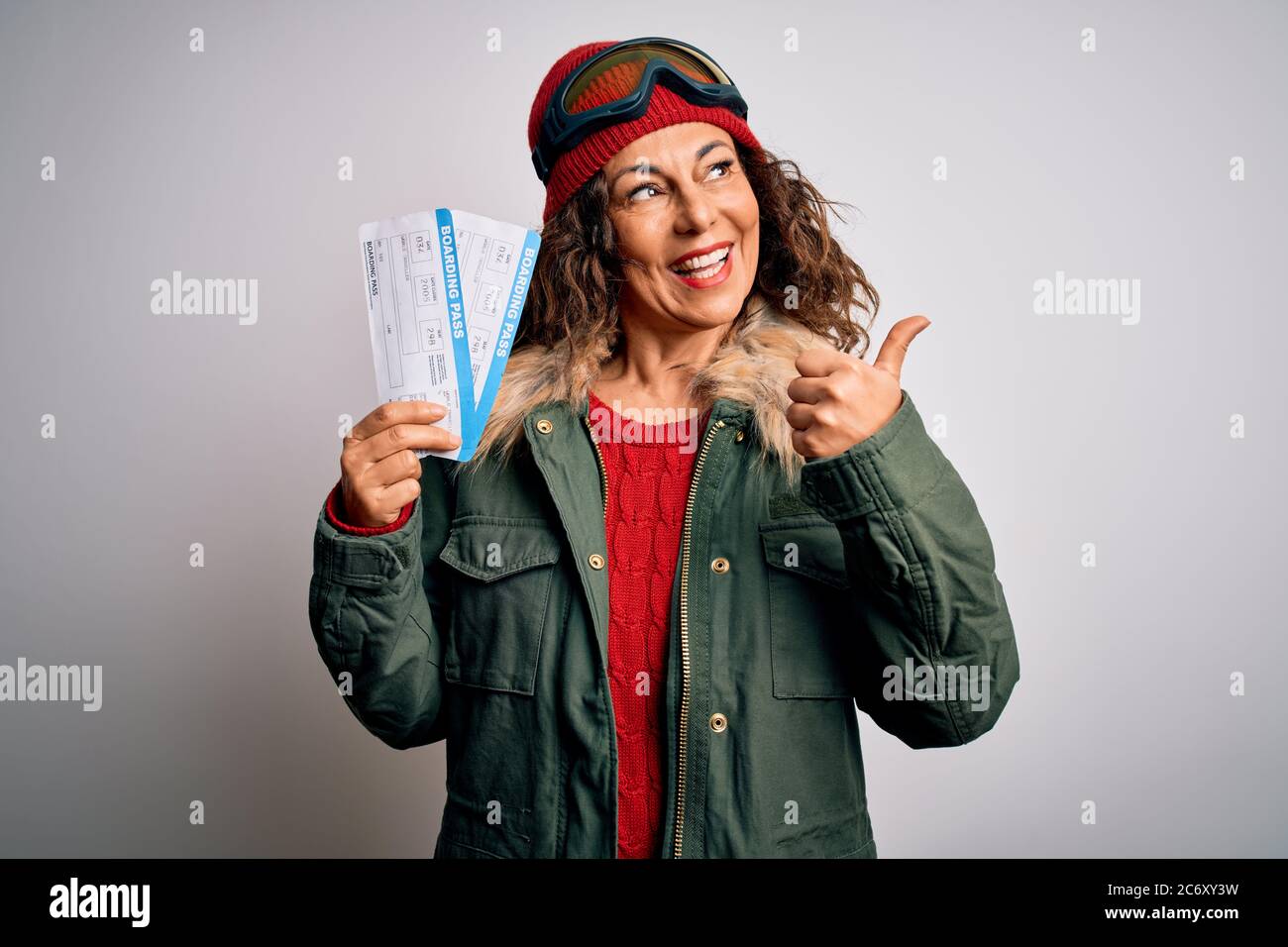 Middle age tourist woman wearing skier goggles holding airline boarding ...