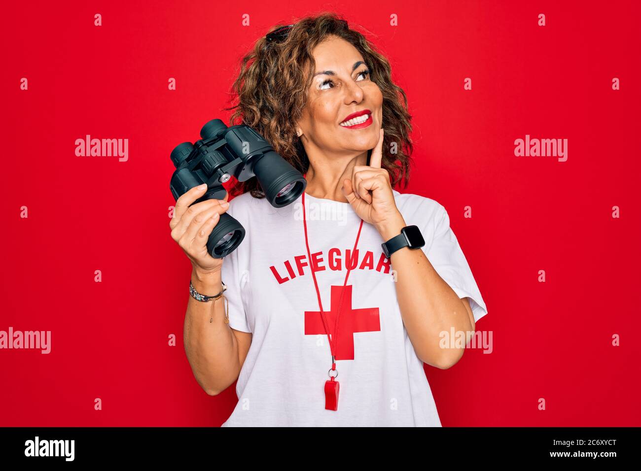 Middle age senior summer lifeguard woman looking through binoculars ...