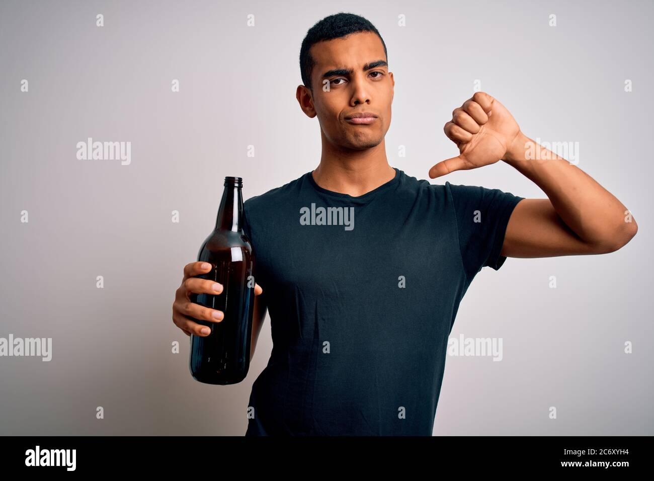Young handsome african american man drinking bottle of beer over white ...