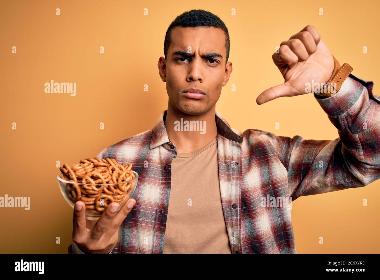 Young handsome african american man holding bowl with german baked ...