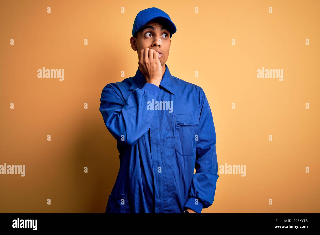 Young african american mechanic man wearing blue uniform and cap over ...