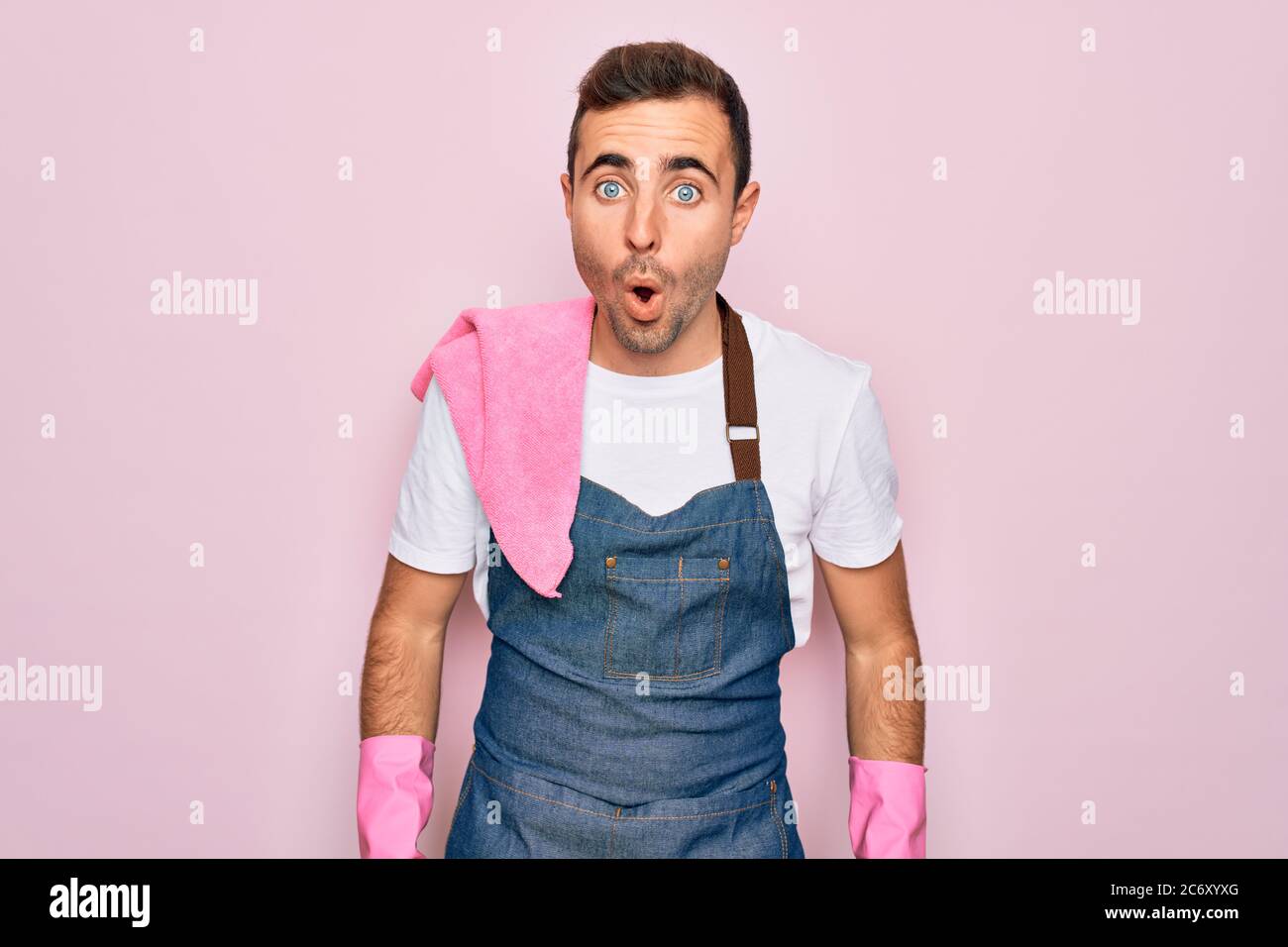 Young cleaner man with blue eyes cleaning wearing apron and gloves over ...