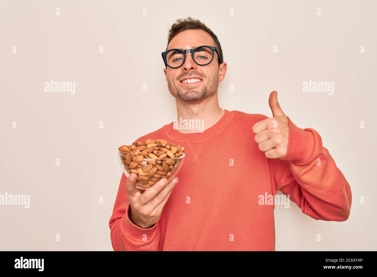 Handsome man with blue eyes holding bowl with healthy almonds snack ...