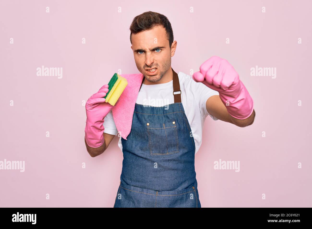 Young cleaner man with blue eyes cleaning wearing apron and gloves ...