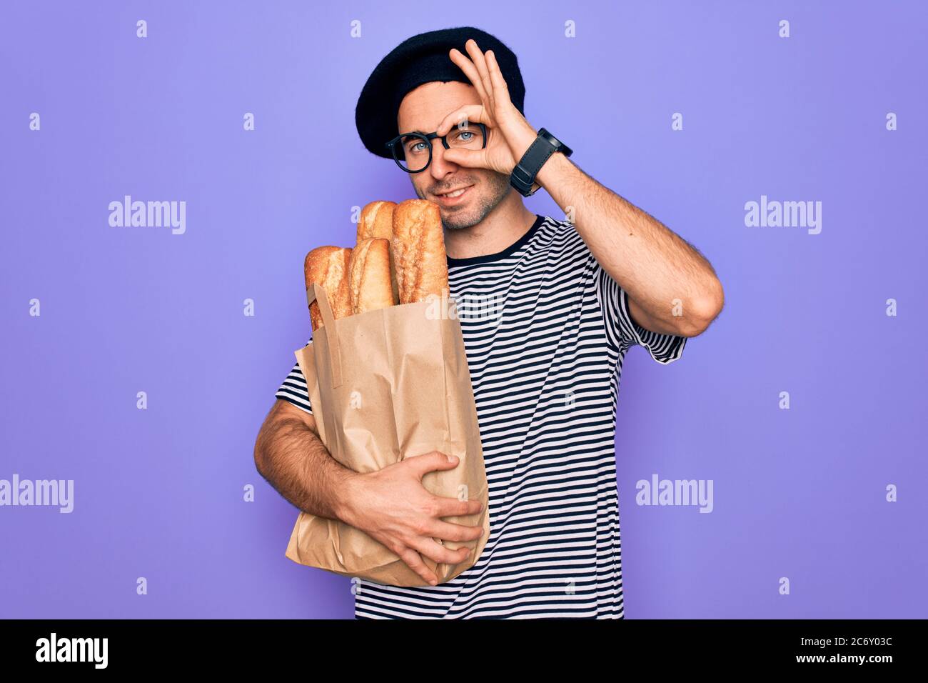 Young handsome baker man with blue eyes wearing french beret holding ...