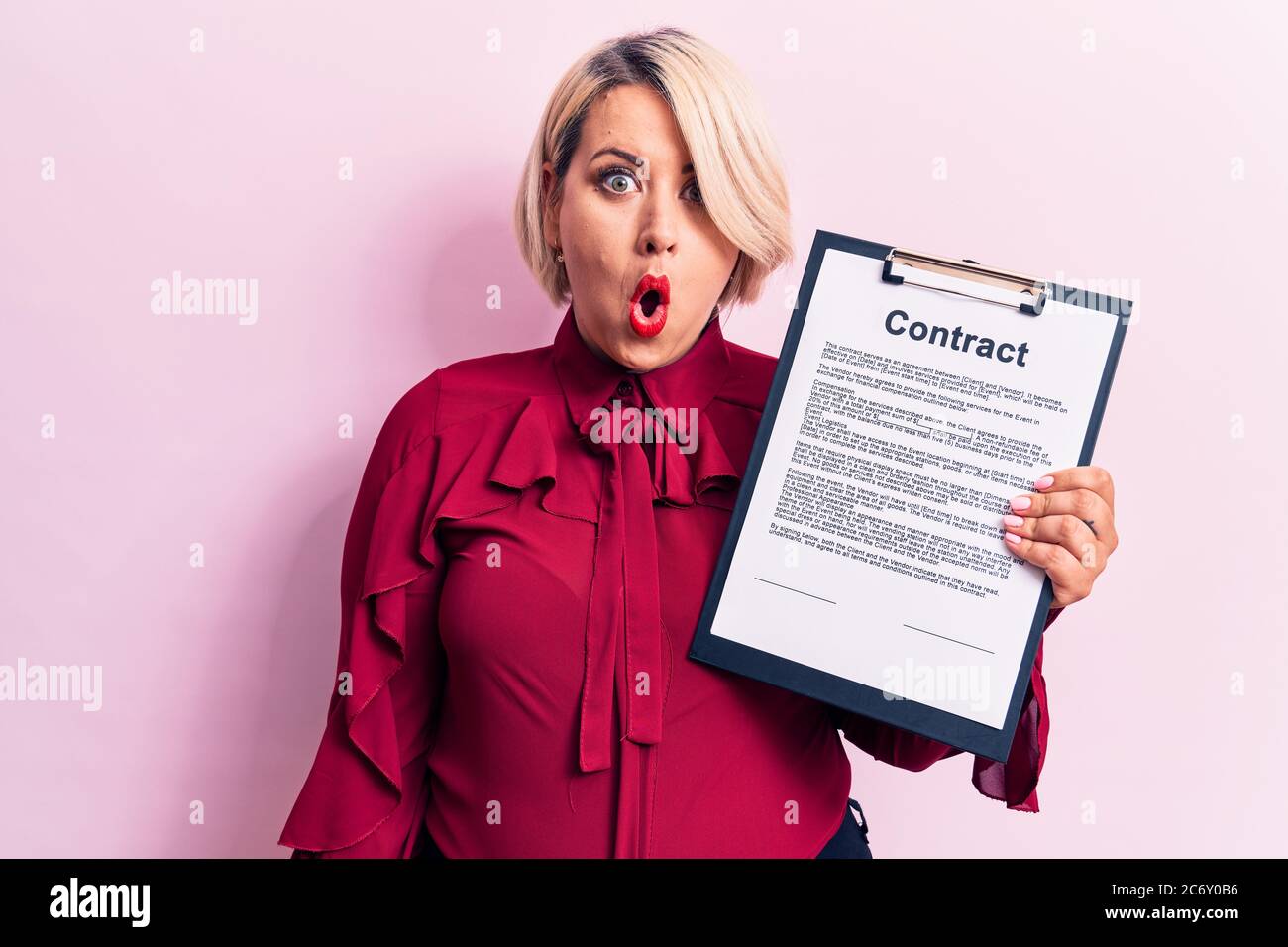Young beautiful blonde plus size woman holding clipboard with contract ...