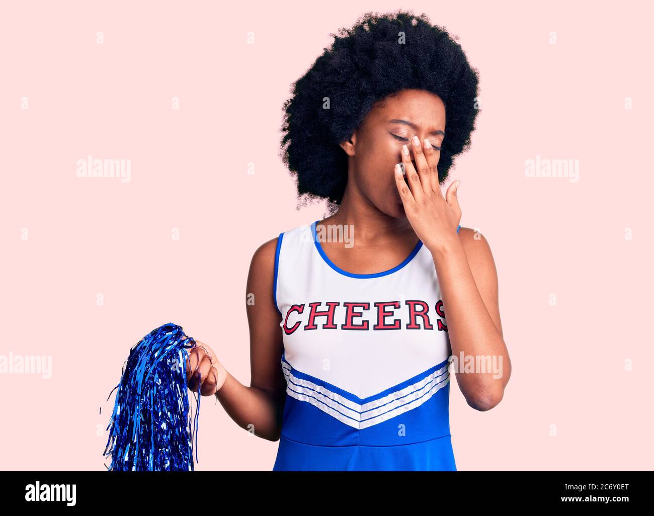 Young african american woman wearing cheerleader uniform holding pompom ...