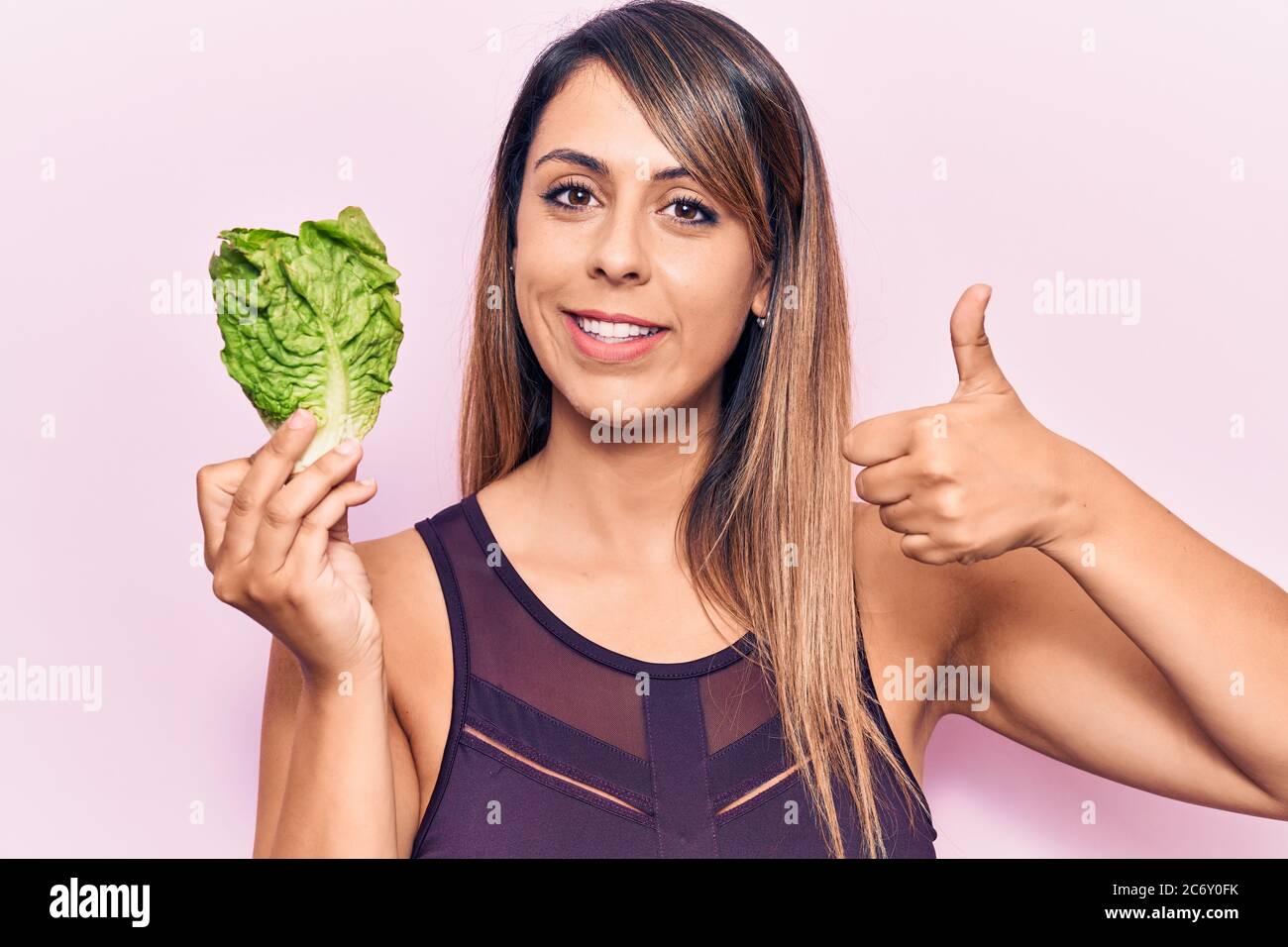 Young beautiful woman holding lettuce smiling happy and positive, thumb ...