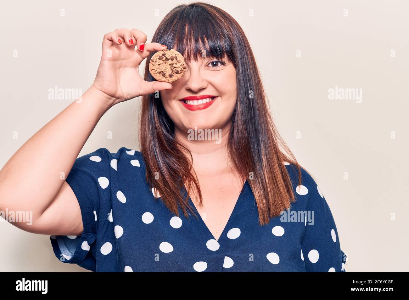 Young plus size woman holding chocolate cookie looking positive and ...
