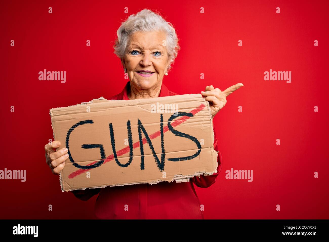 Senior beautiful grey-haired woman holding banner with prohibited guns ...
