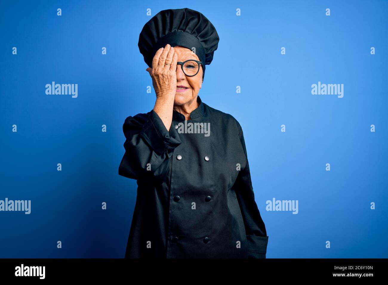 Senior beautiful grey-haired chef woman wearing cooker uniform and hat ...
