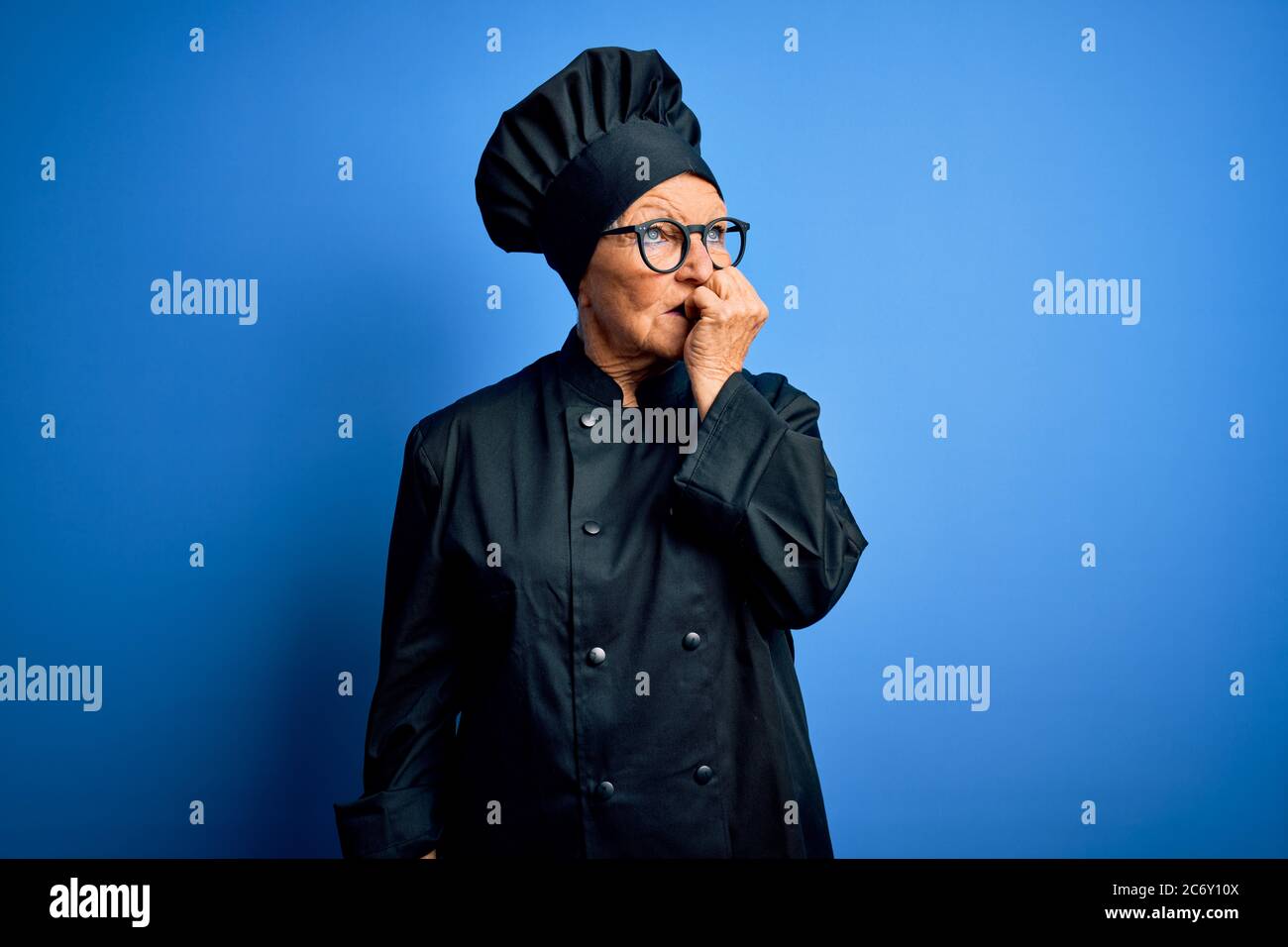 Senior beautiful grey-haired chef woman wearing cooker uniform and hat ...