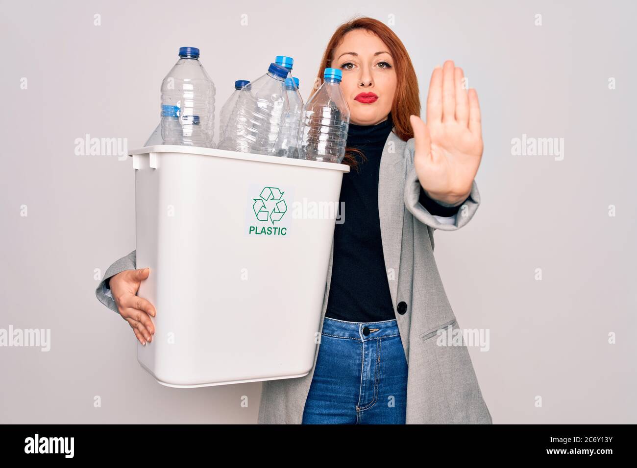 Young beautiful redhead woman recycling holding trash can with plastic ...