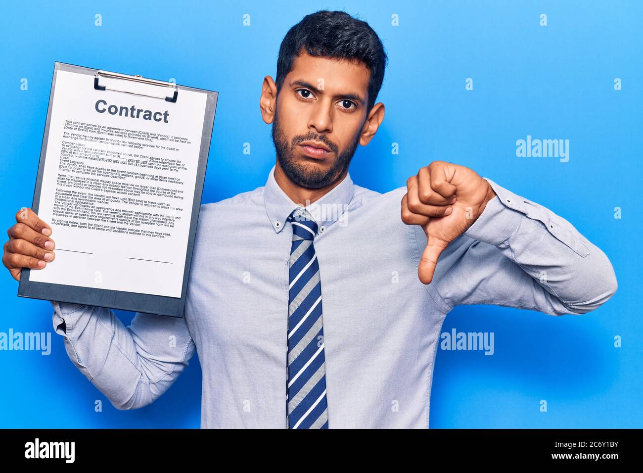 Young latin man holding clipboard with contract document with angry ...