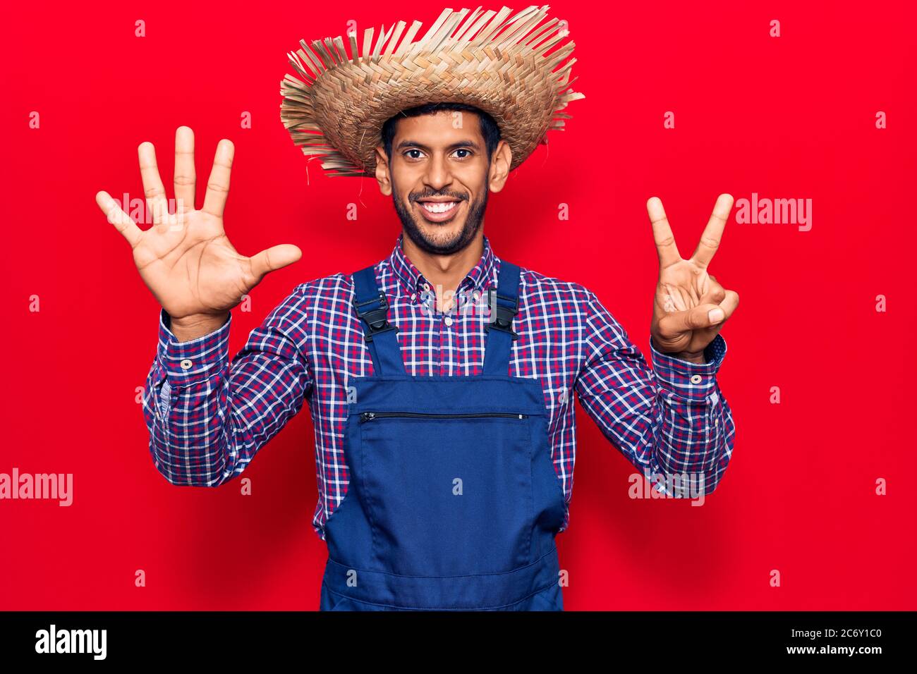 Young latin man wearing farmer hat and apron showing and pointing up ...
