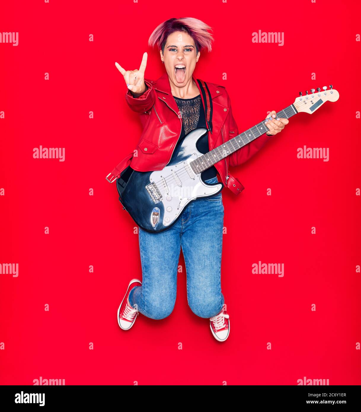 Young beautiful guitarist woman with pink short hair playing electric ...