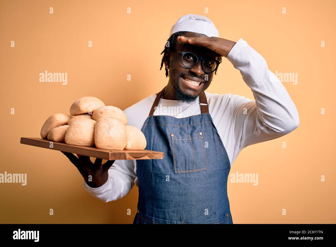 Young african american baker man wearing apron holding tray with ...