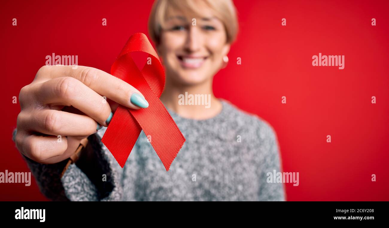 Young blonde woman with short hair holding hiv and aids awareness red ...