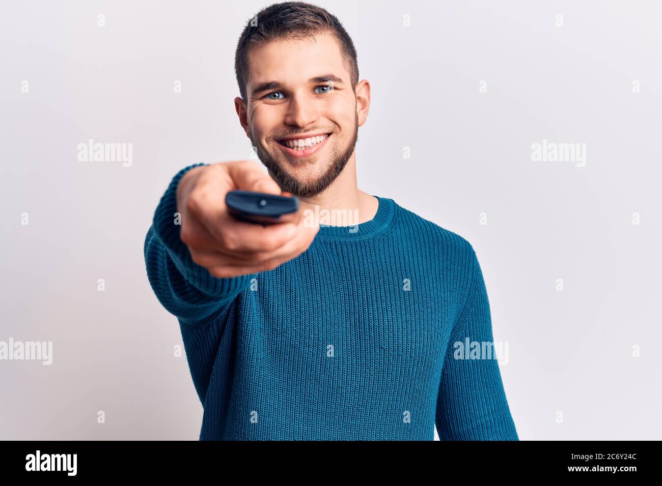 Young handsome man holding tv remote control looking positive and happy ...