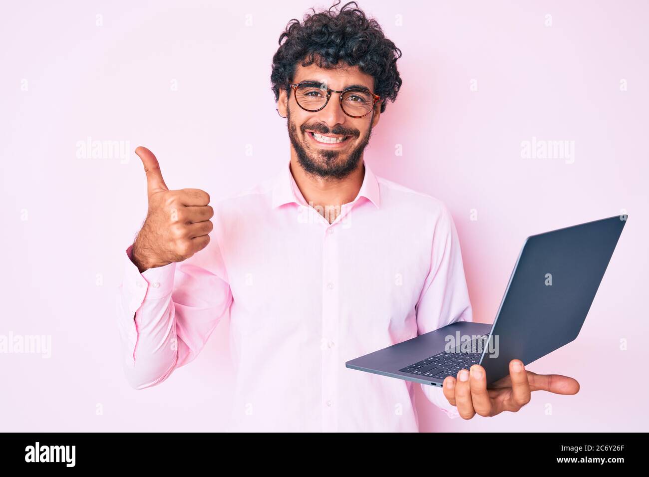 Handsome young man with curly hair and bear working using computer ...