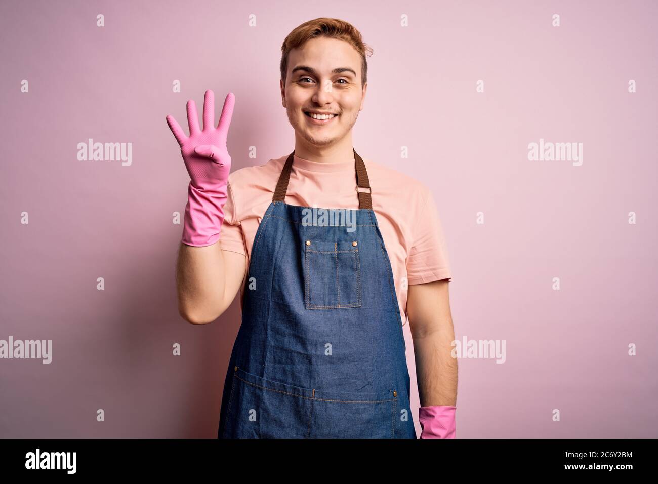 Young Handsome Redhead Cleaner Man Doing Housework Wearing Apron And Gloves Showing And Pointing