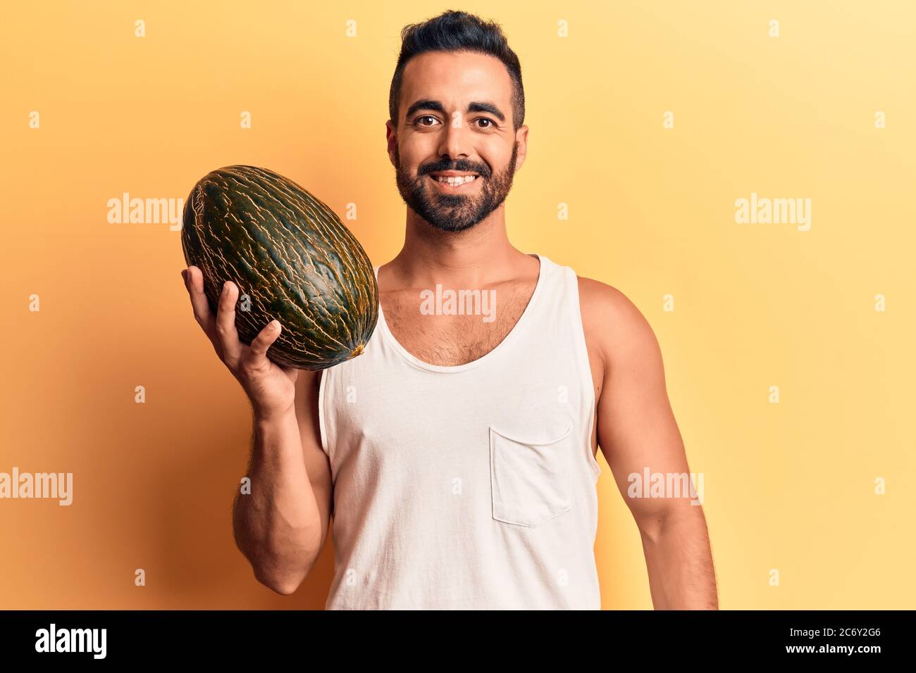 Young hispanic man holding melon looking positive and happy standing ...