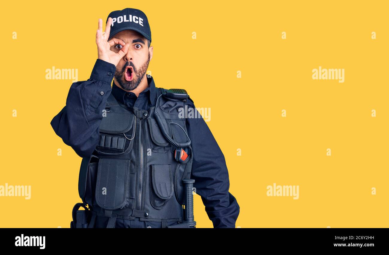 Young hispanic man wearing police uniform doing ok gesture shocked with ...